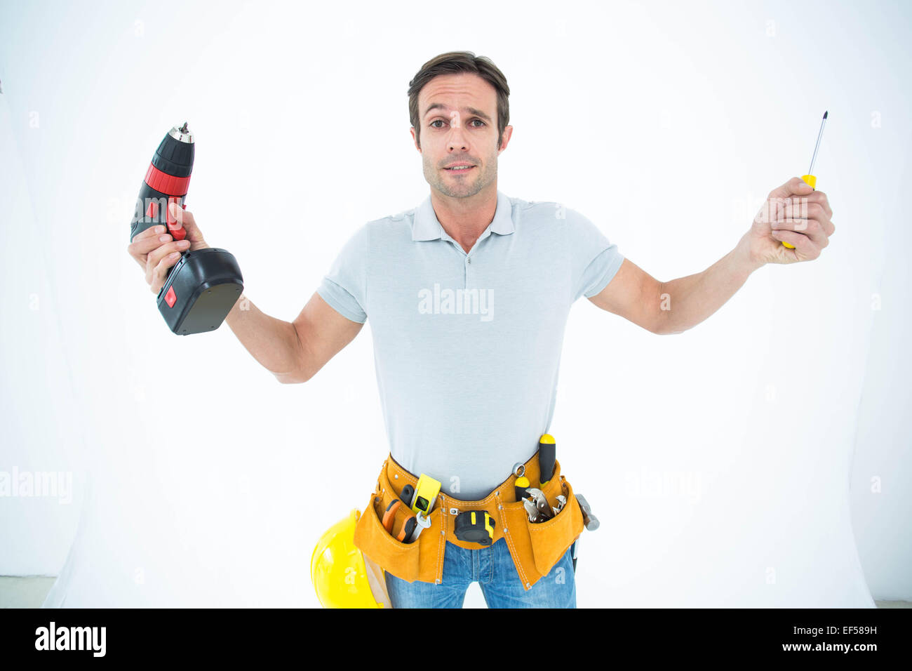 Confused technician holding screwdriver and drill machine Stock Photo ...