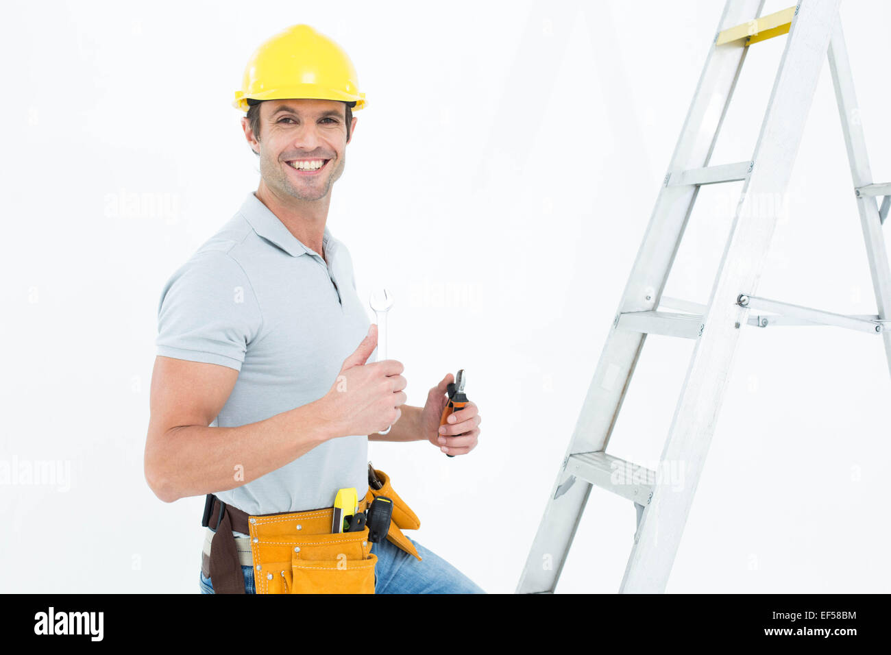 Technician with tools showing thumbs up by step ladder Stock Photo - Alamy