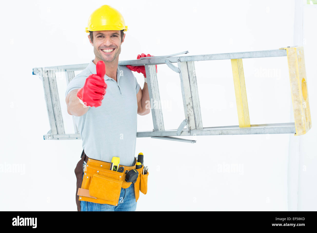 Worker carrying step ladder while showing thumbs up Stock Photo - Alamy