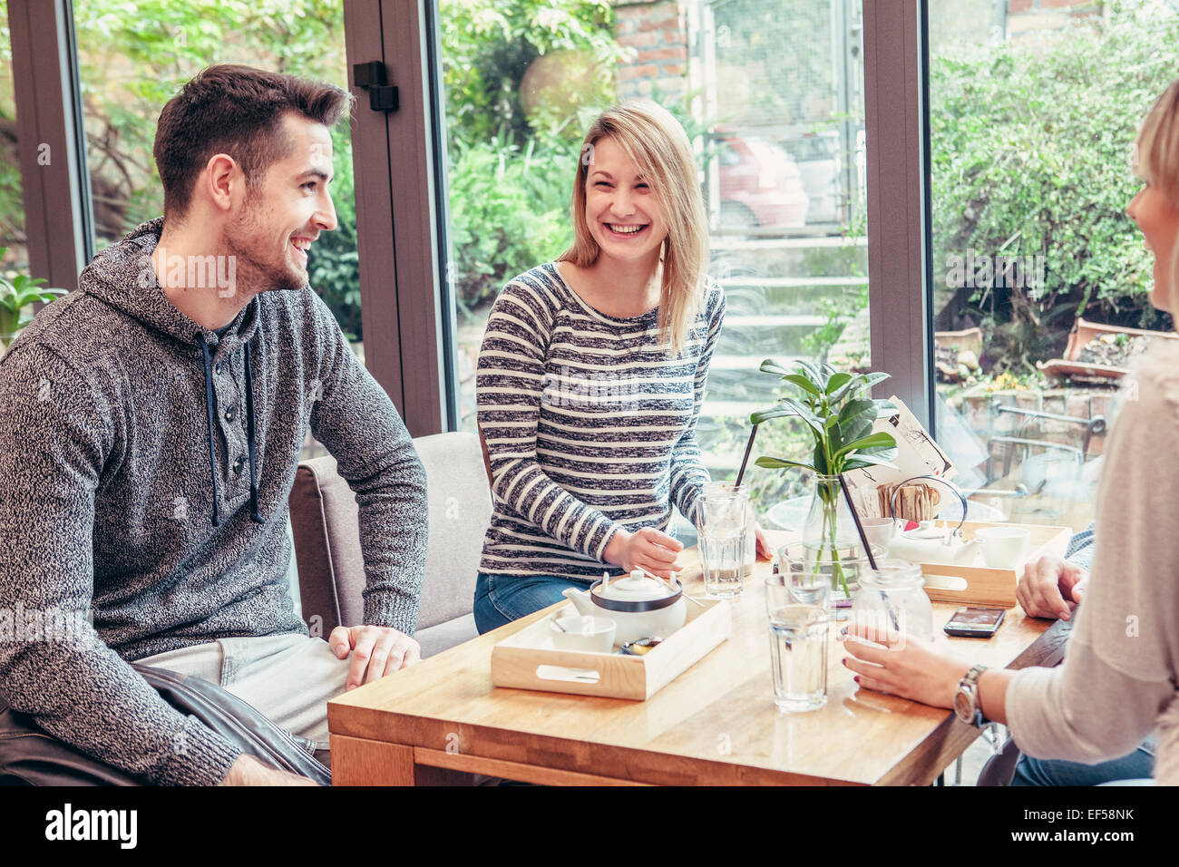 Three friends talking and having fun while drinking coffee hi-res stock ...