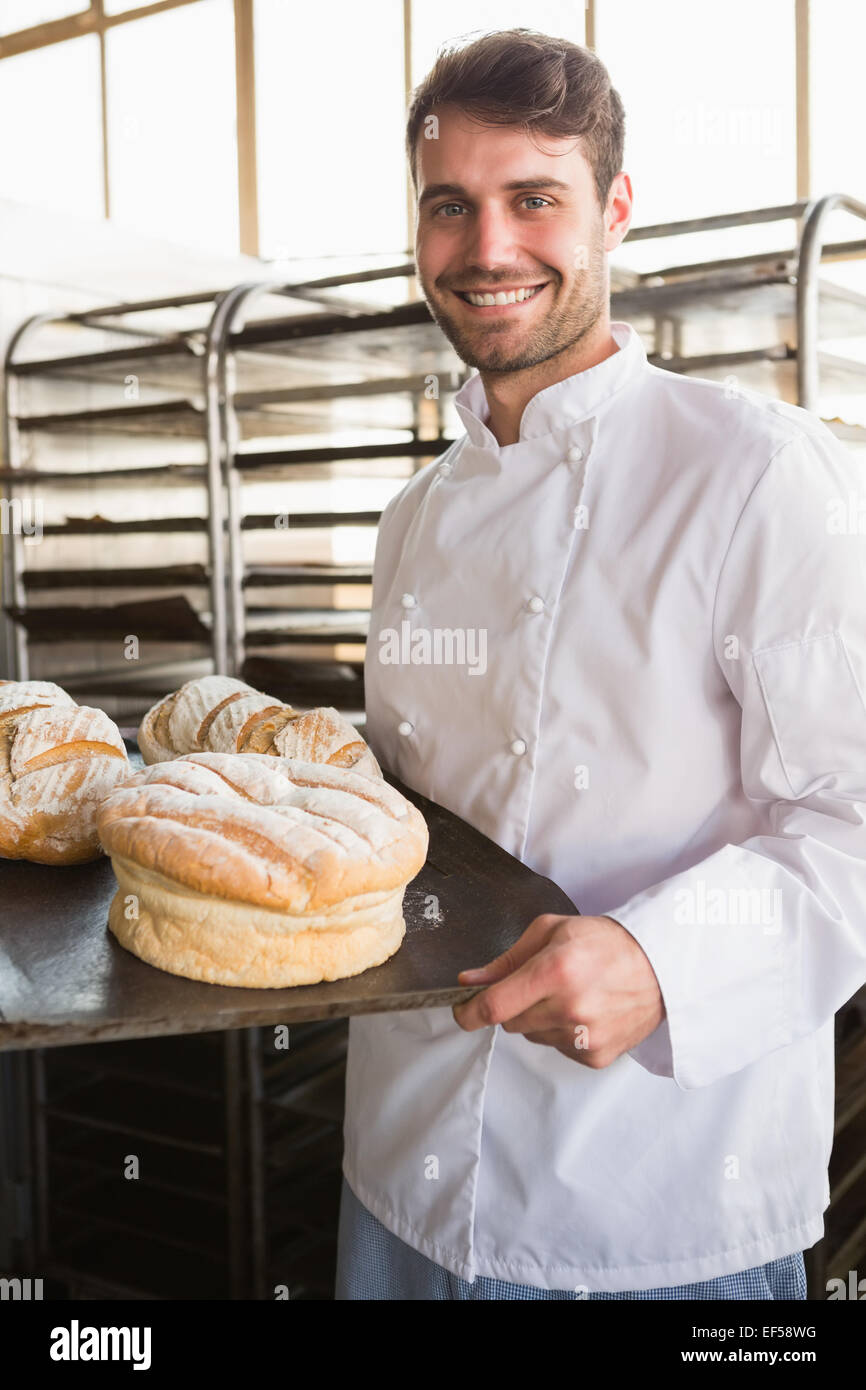 Happy baker showing tray with bread Stock Photo - Alamy