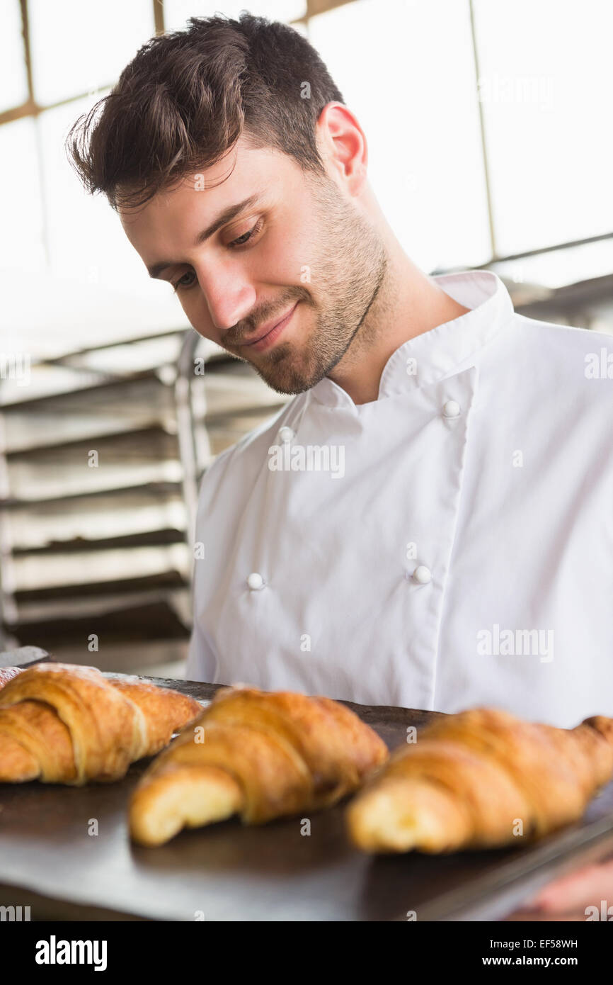 Baker showing tray of fresh croissant Stock Photo - Alamy