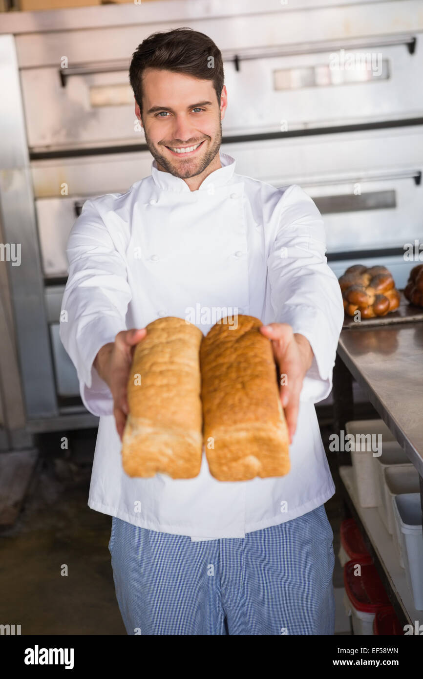 Smiling baker showing loaves of bread Stock Photo - Alamy