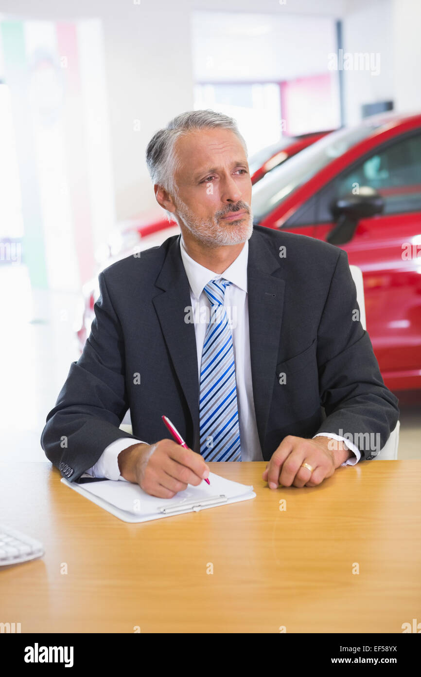 Focused salesman writing on clipboard at his desk Stock Photo - Alamy