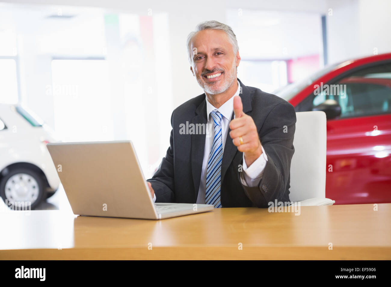 Smiling businessman giving thumbs up using his laptop Stock Photo - Alamy