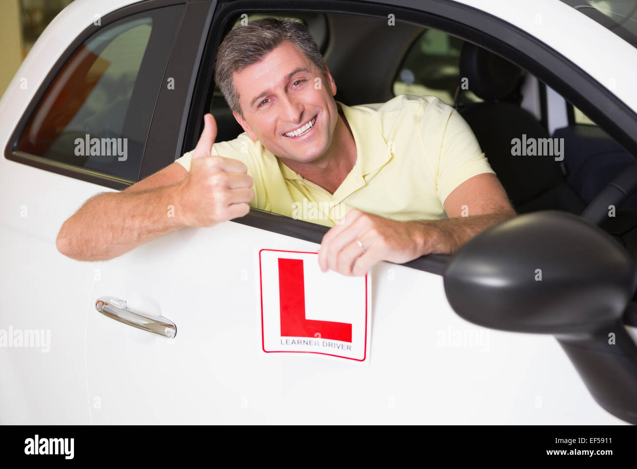 Man gesturing thumbs up holding a learner driver sign Stock Photo - Alamy