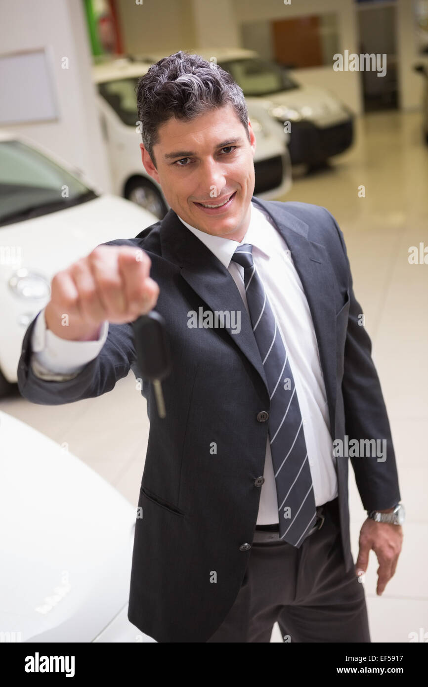 Salesman standing while offering car keys Stock Photo - Alamy