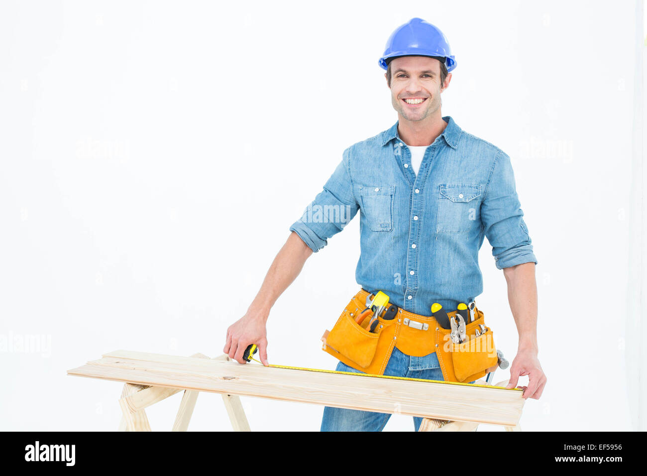Happy male carpenter measuring wooden plank Stock Photo - Alamy