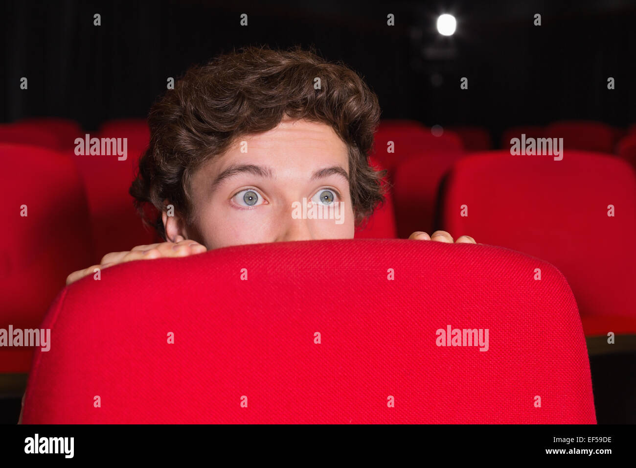 Young man watching a scary film Stock Photo - Alamy