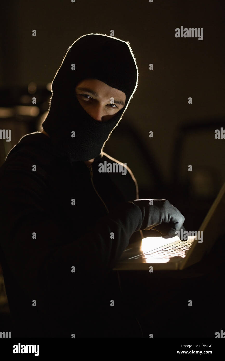 Hooded hacker using laptop hi-res stock photography and images - Alamy