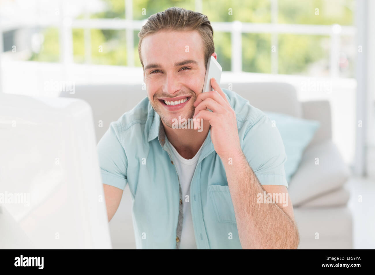 Smiling businessman on the phone while using computer Stock Photo - Alamy