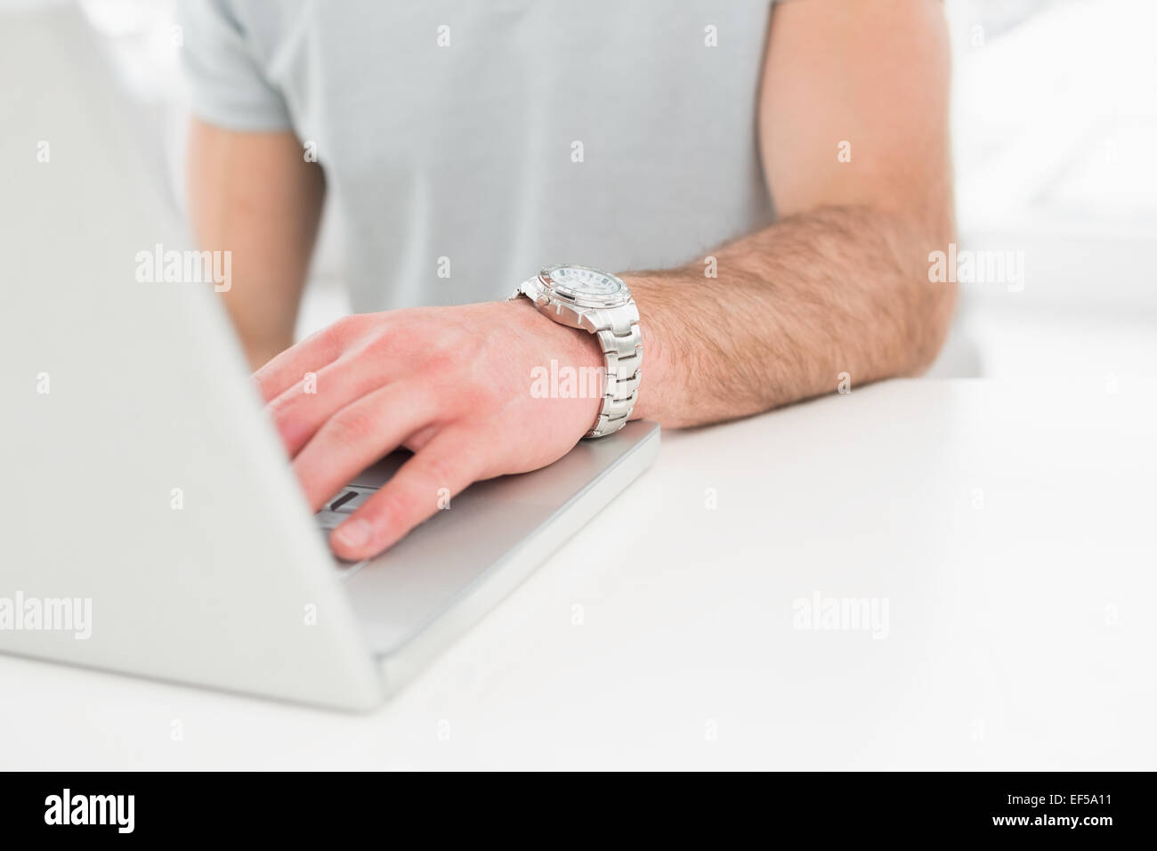 Businessman with watch using laptop Stock Photo - Alamy