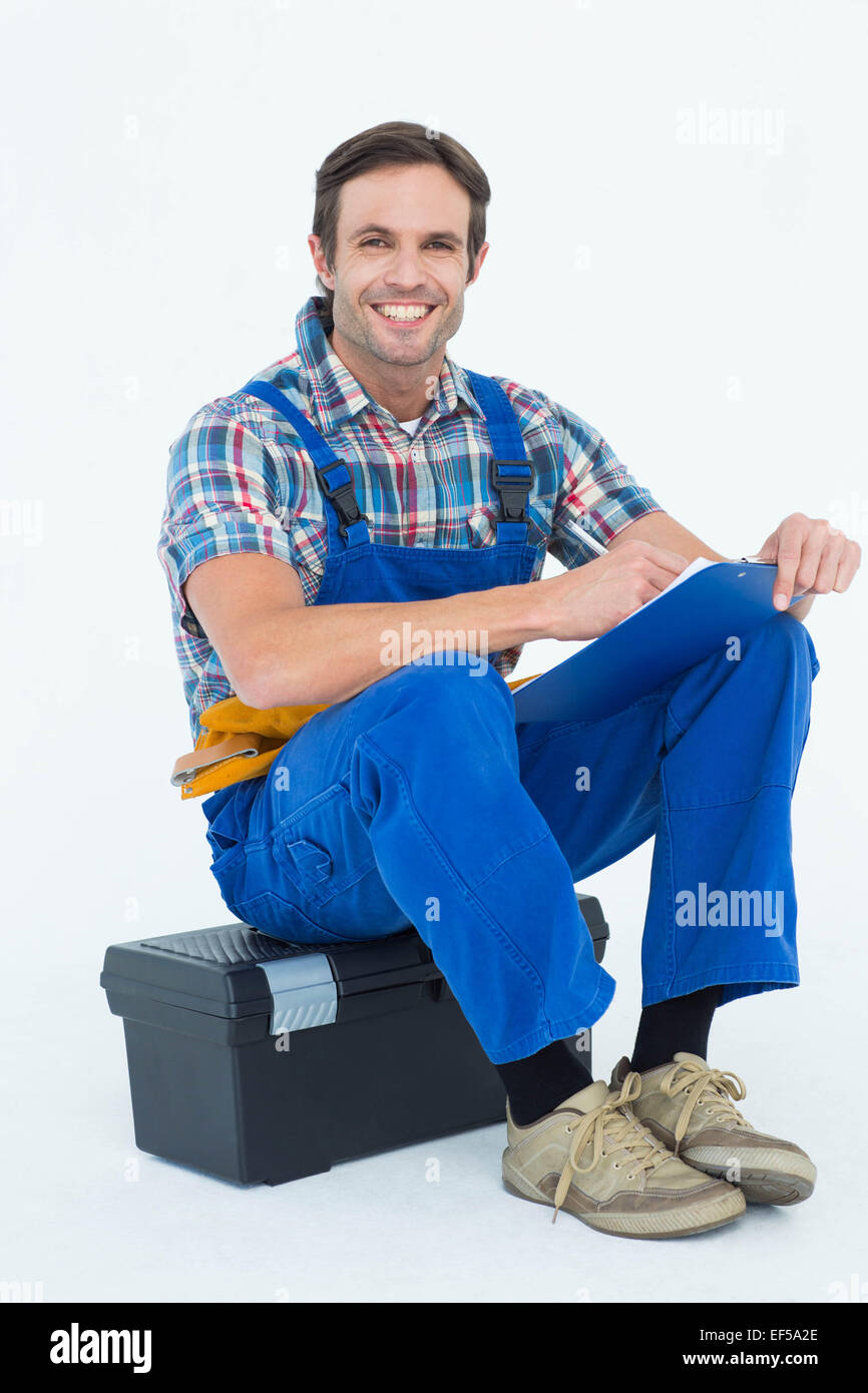 Plumber writing notes while sitting on tool box Stock Photo - Alamy
