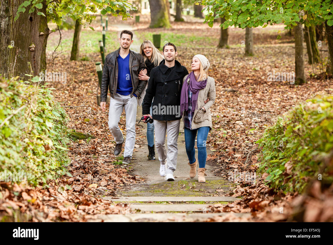 Group of friends walking through autumn park Stock Photo - Alamy