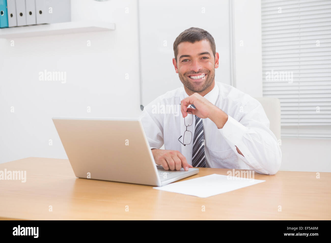 Smiling businessman using his computer at his desk Stock Photo - Alamy