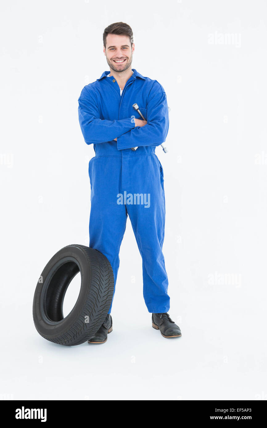 smiling mechanic with arms crossed standing by tire Stock Photo - Alamy