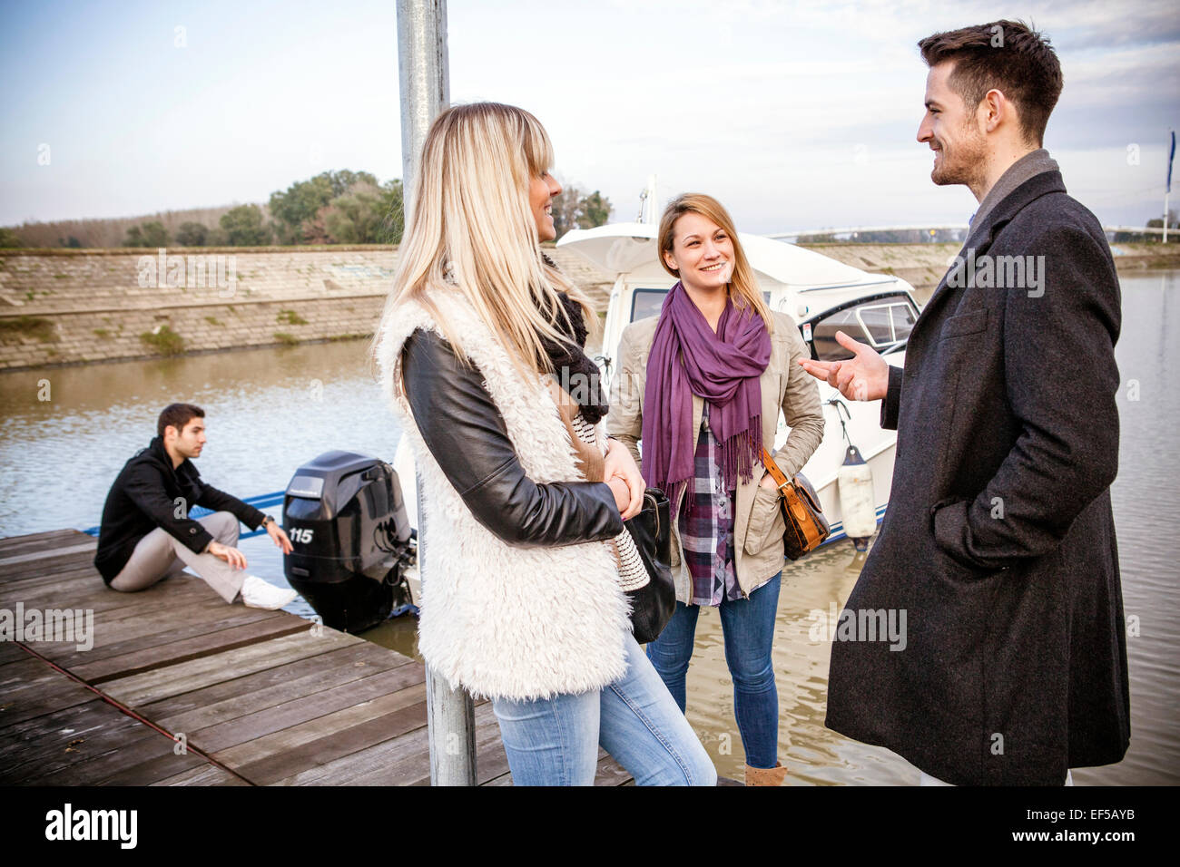 Group of friends on jetty, motorboat in background Stock Photo - Alamy