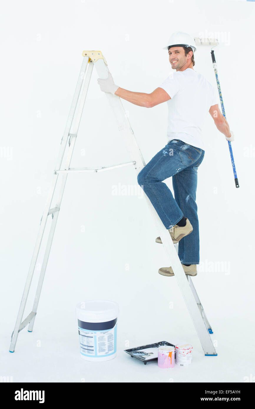 Happy man on ladder painting with roller Stock Photo - Alamy