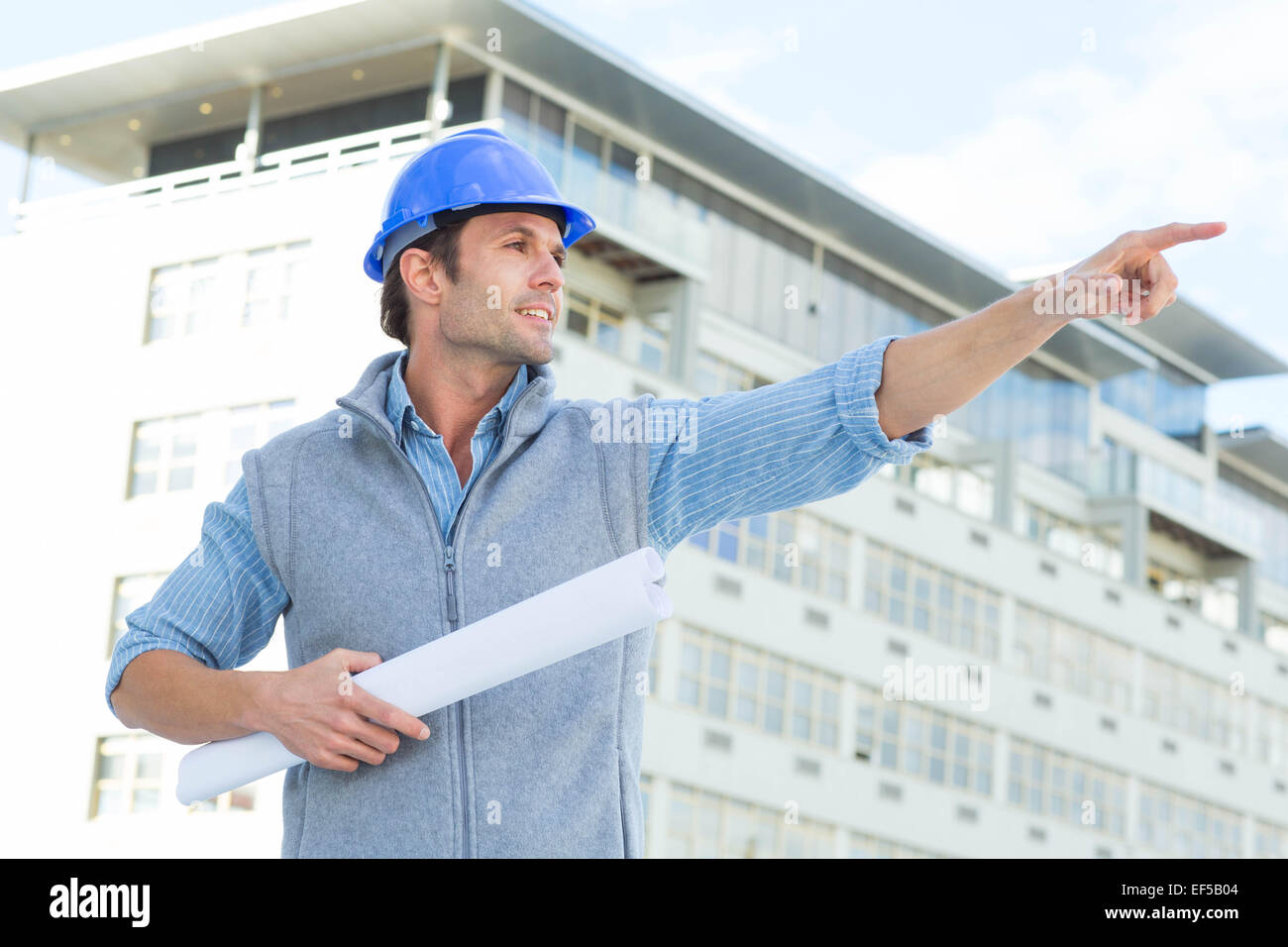 Architect with blueprint pointing away Stock Photo - Alamy