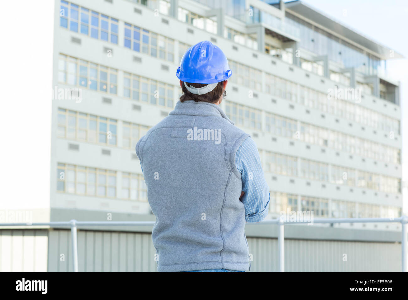 Architect wearing hard hat while looking at building Stock Photo - Alamy