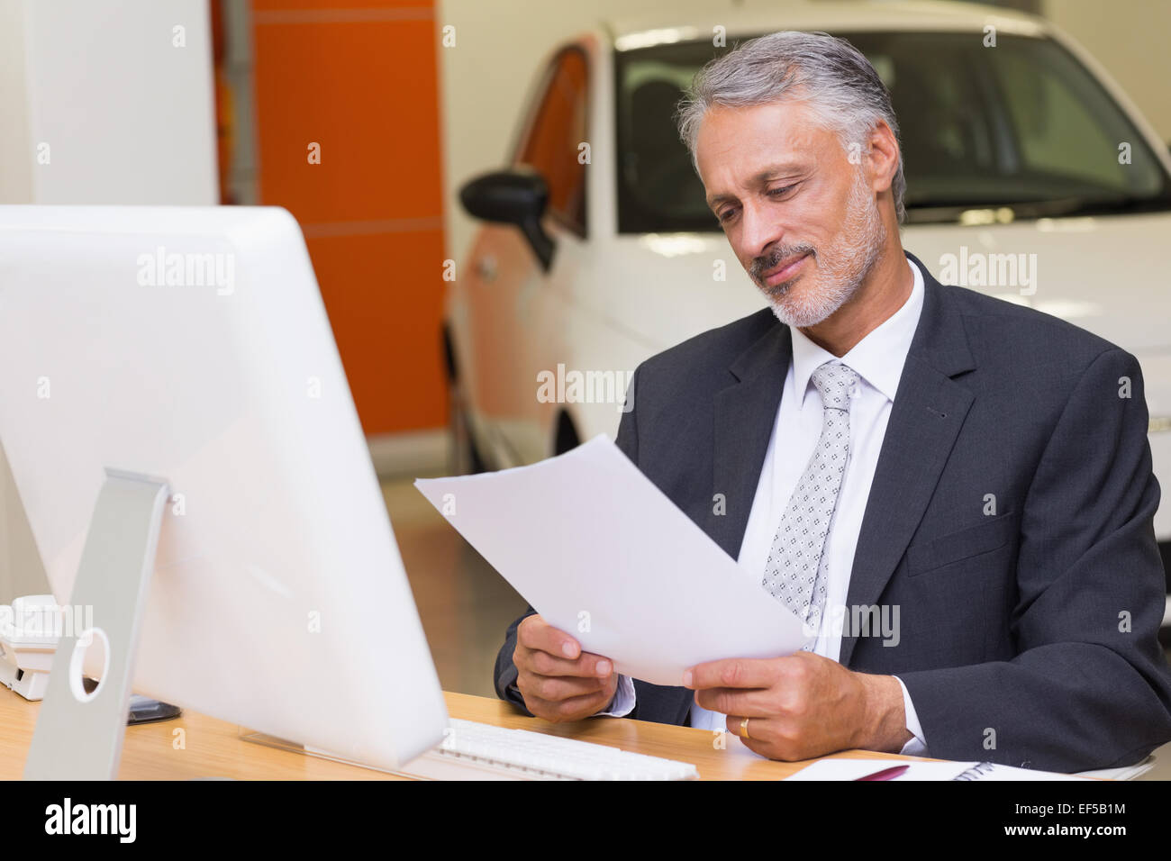 Businessman reading document at office desk Stock Photo - Alamy