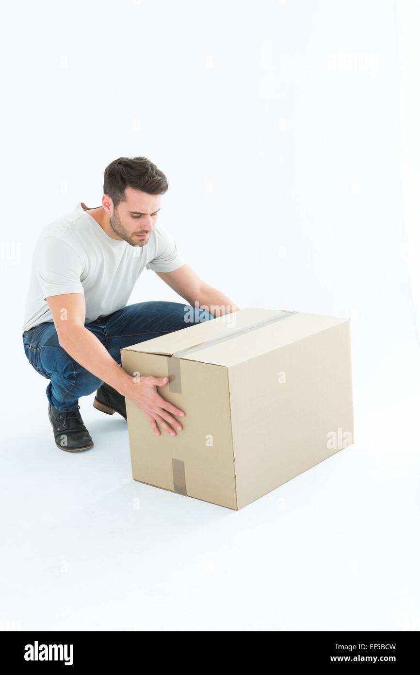 Delivery man crouching while picking cardboard box Stock Photo - Alamy