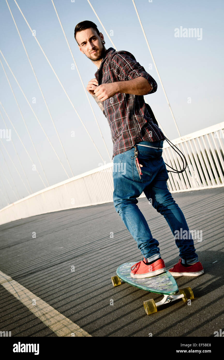 Young man skateboarding across bridge Stock Photo - Alamy