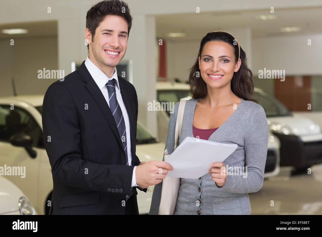 Salesperson showing clipboard to sign to customer Stock Photo - Alamy