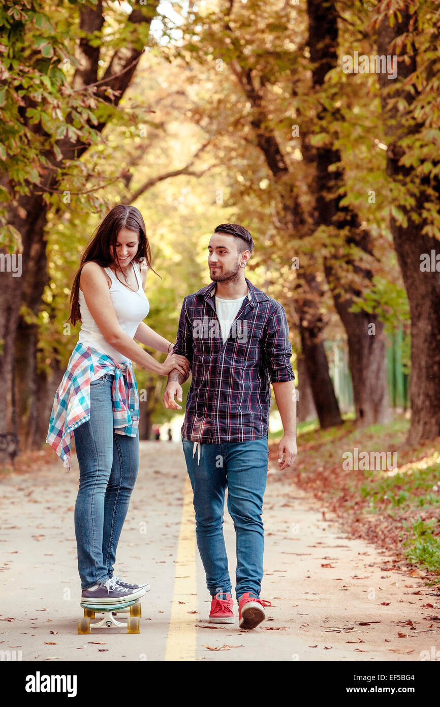 Young couple skateboarding through park Stock Photo - Alamy