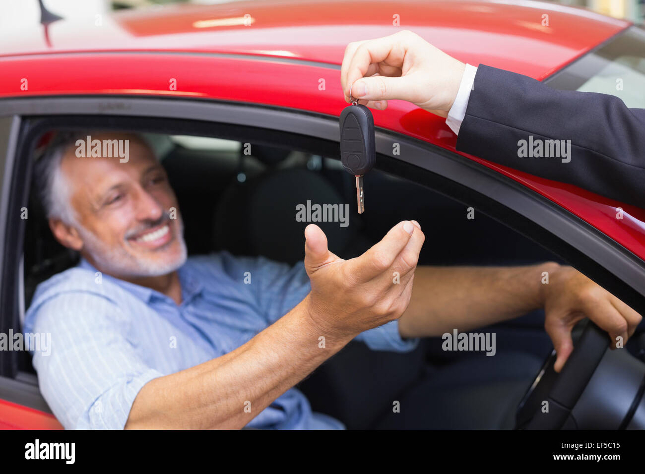 Smiling man driving a car while salesman his giving key Stock Photo - Alamy