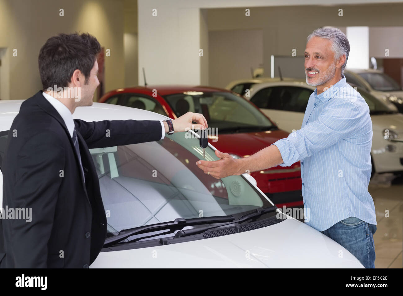 Smiling businessman giving car key to happy customer Stock Photo - Alamy