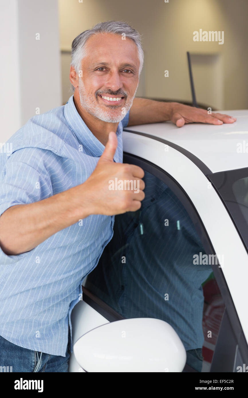 Smiling man hugging a white car while giving thumbs up Stock Photo - Alamy