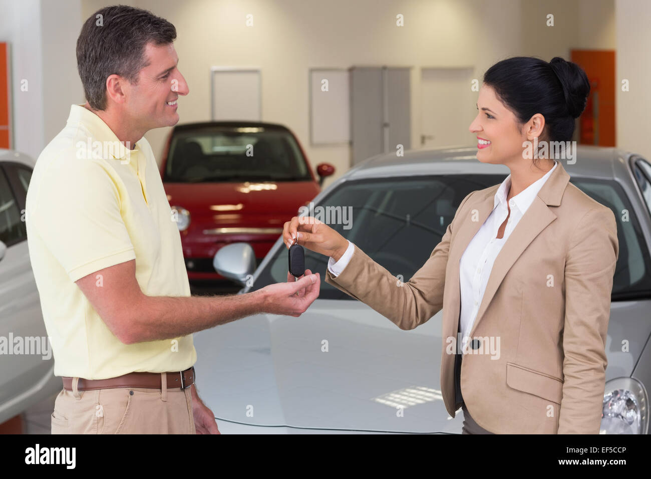 Smiling businesswoman giving car key to happy customer Stock Photo - Alamy