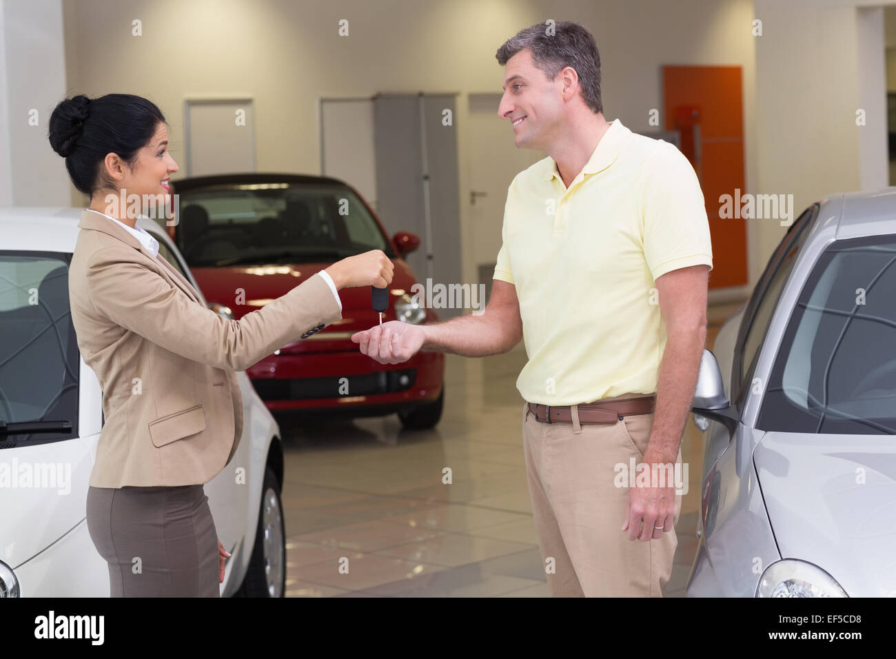Smiling businesswoman giving car key to happy customer Stock Photo - Alamy