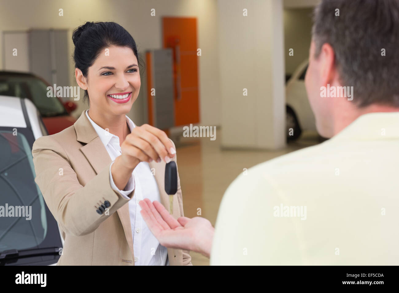 Smiling businesswoman giving car key to happy customer Stock Photo - Alamy