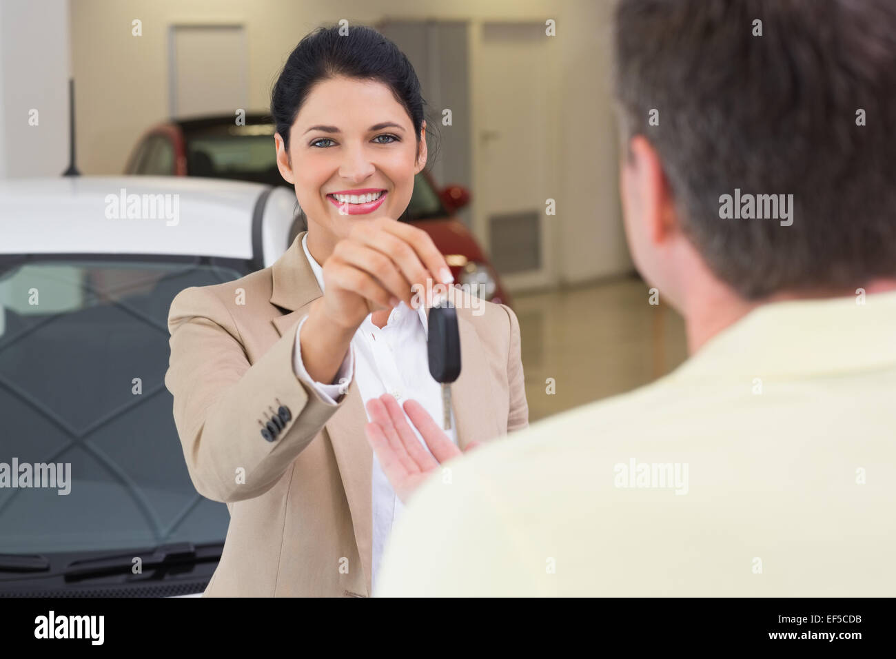 Smiling businesswoman giving car key to happy customer Stock Photo - Alamy