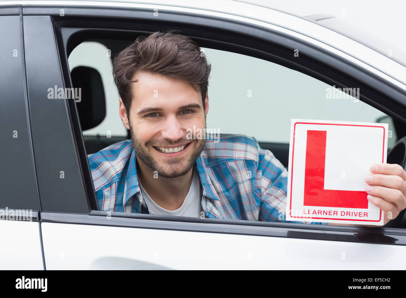 Learner driver smiling and holding l plate Stock Photo - Alamy