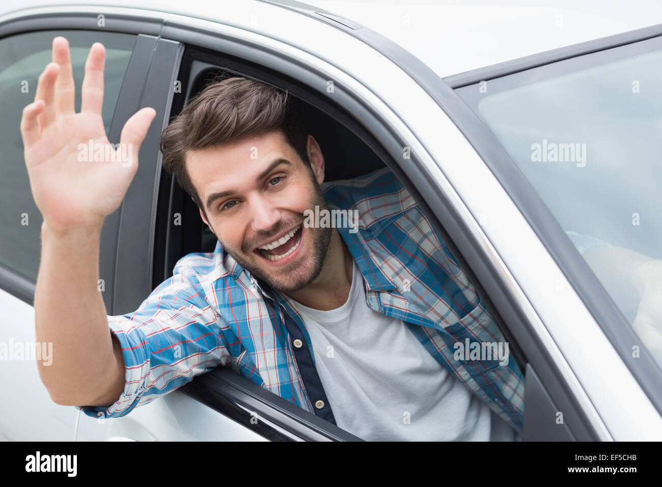 Young man smiling and waving Stock Photo - Alamy