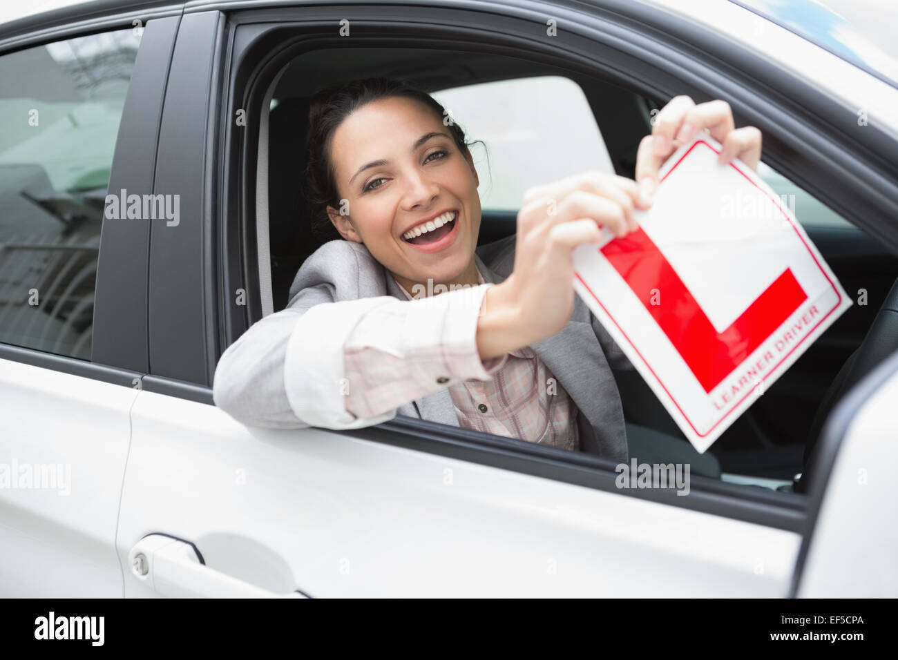 Smiling female driver tearing up her L sign Stock Photo - Alamy