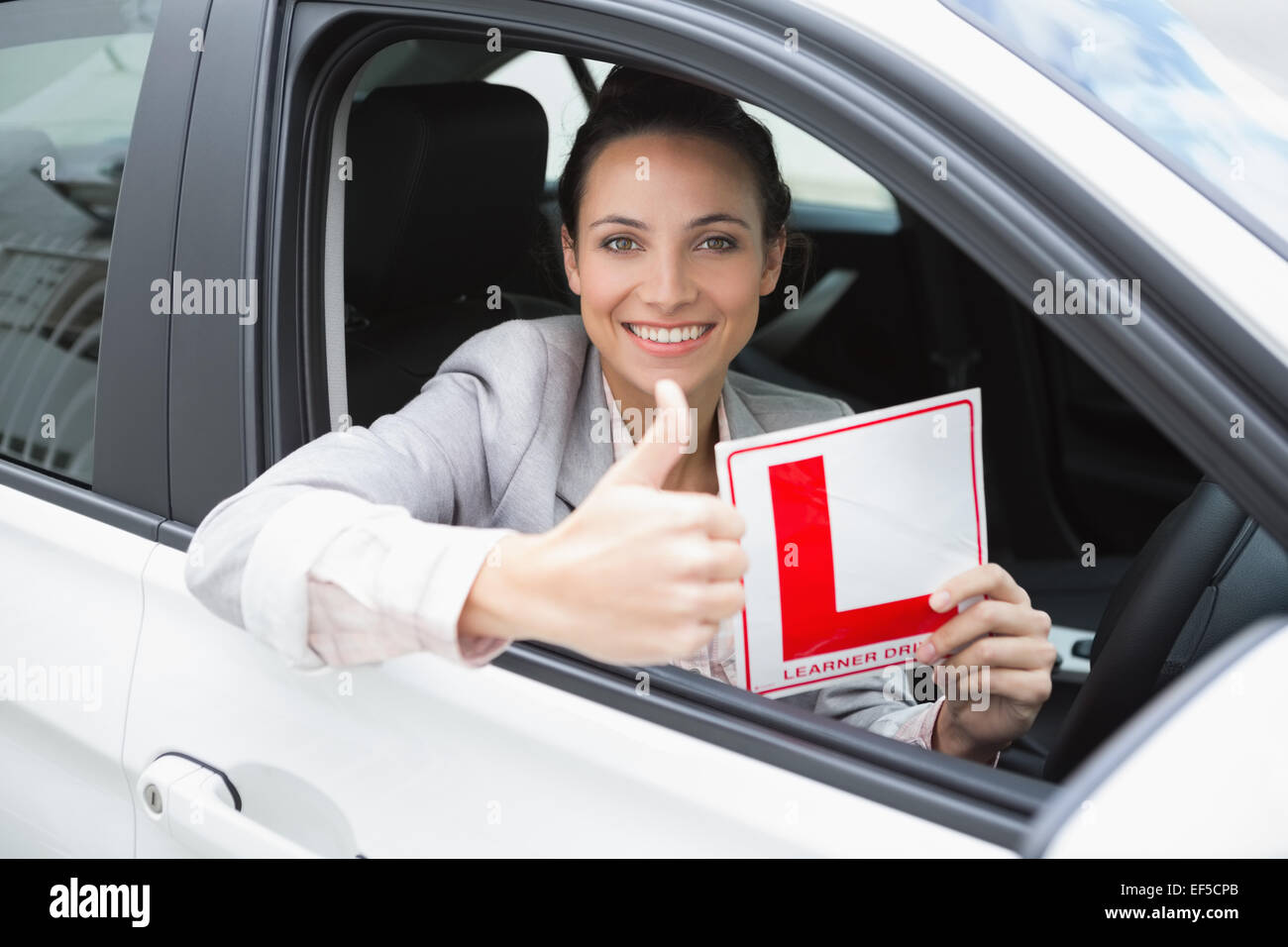 Female driver giving thumbs up while holding her L sign Stock Photo - Alamy