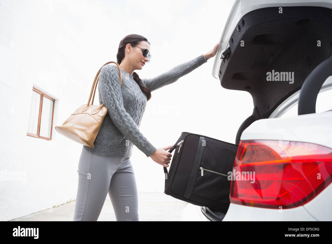 Woman pulling out a baggage of her car trunk Stock Photo - Alamy