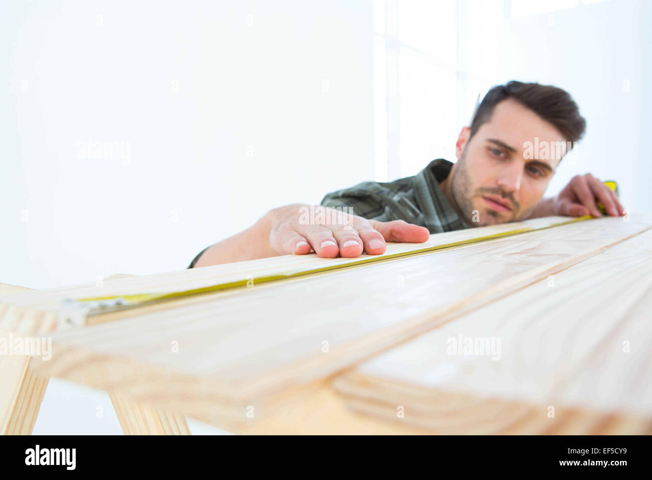 Worker measuring wooden plank Stock Photo - Alamy