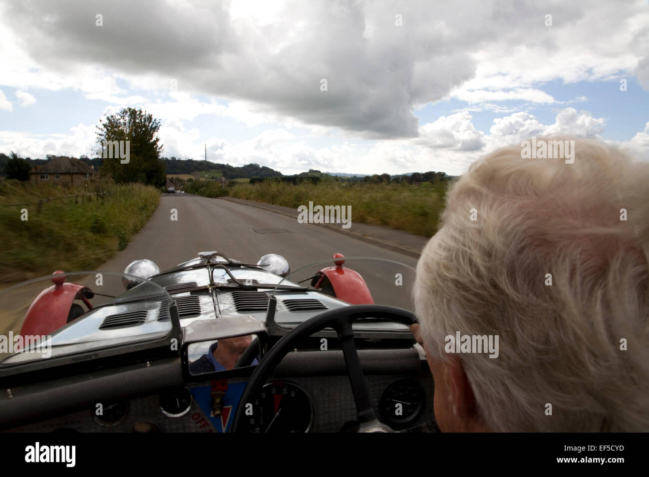 Anonymous driver in open top vintage car driving along English country ...