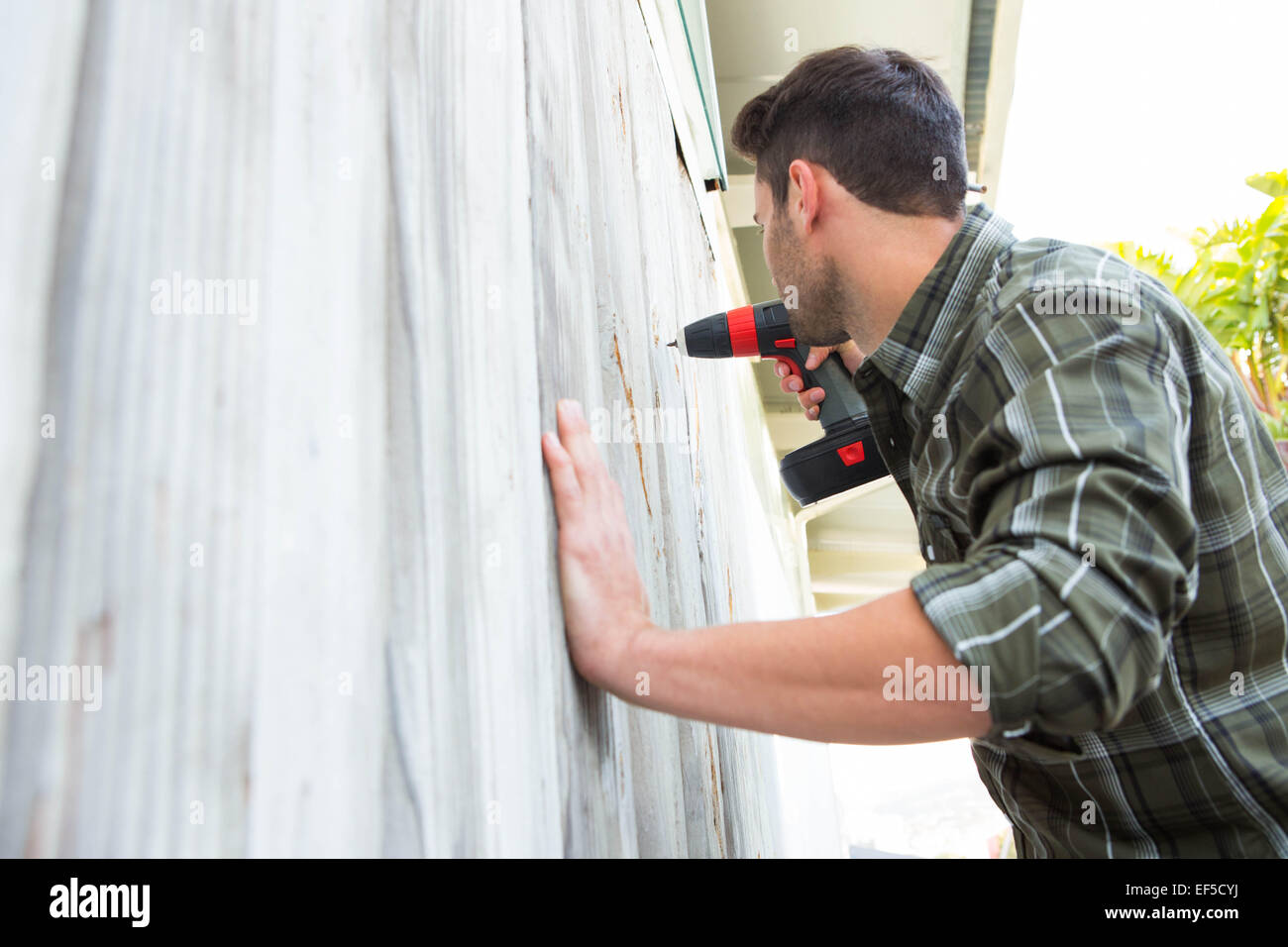 Carpenter drilling wooden cabin Stock Photo - Alamy