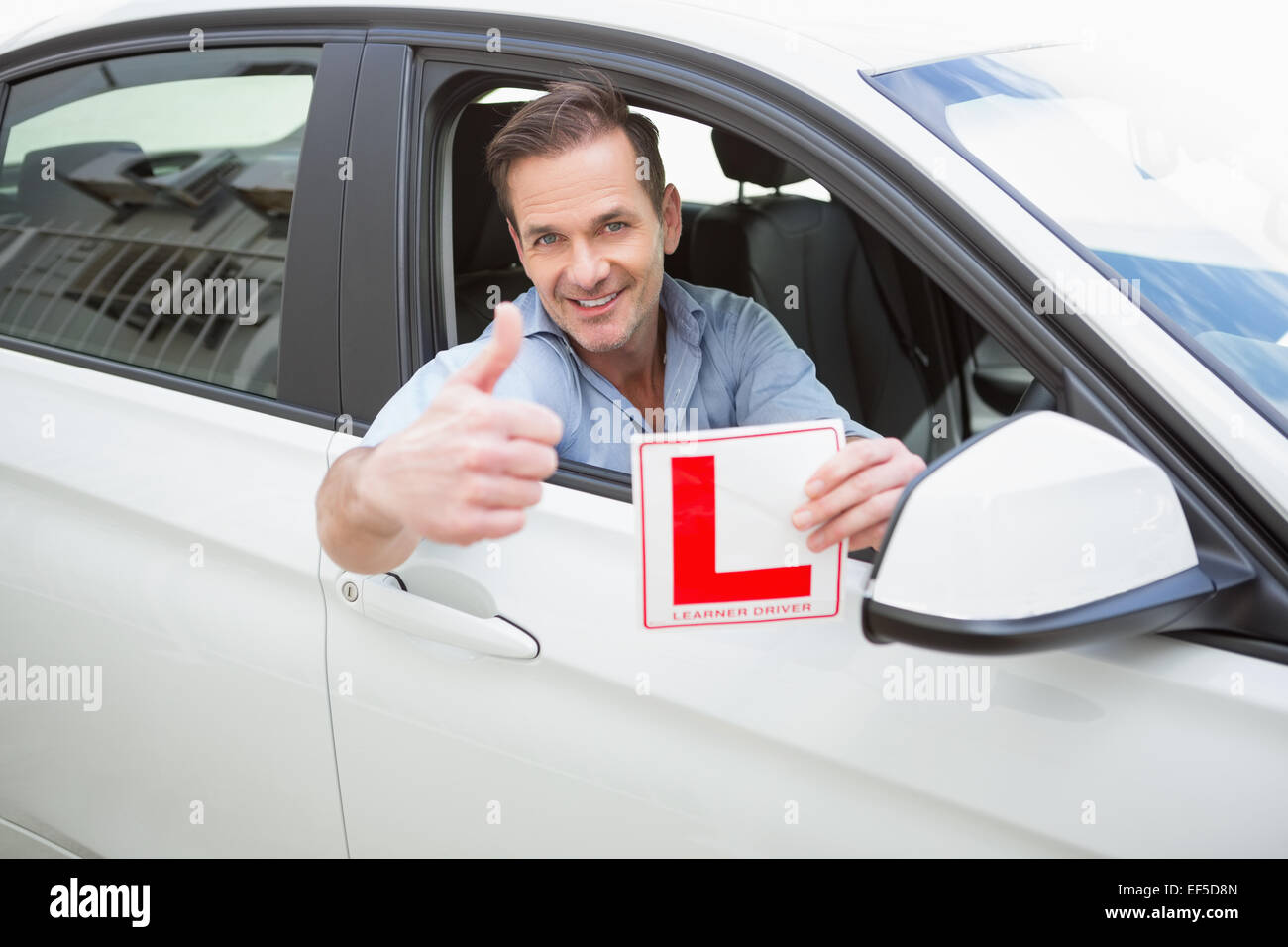 Male driver giving thumbs up while holding his L sign Stock Photo - Alamy