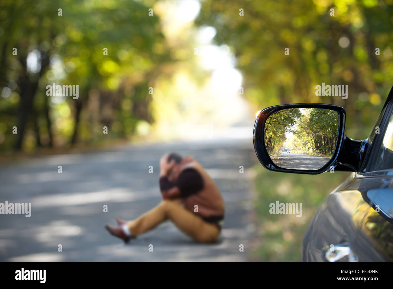 Drive sitting on the road upset at car damage Stock Photo - Alamy