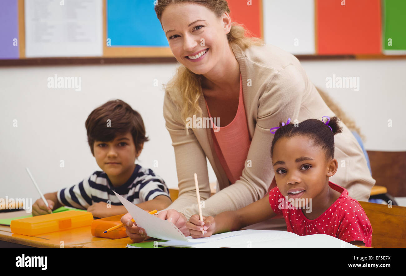 Pretty teacher helping pupil in classroom Stock Photo - Alamy