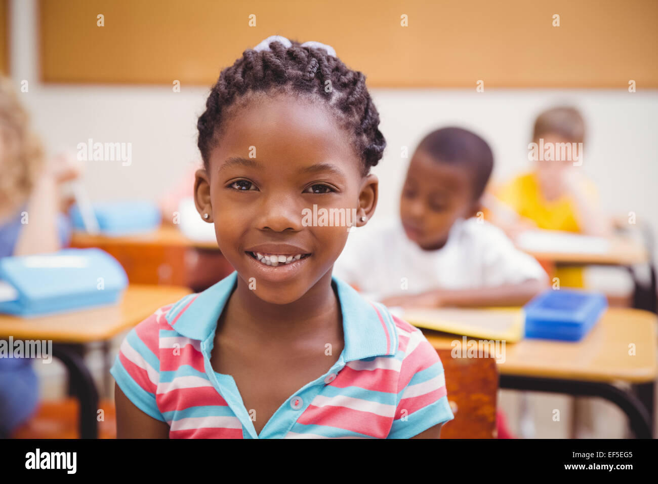 Smiling pupil sitting at her desk Stock Photo - Alamy
