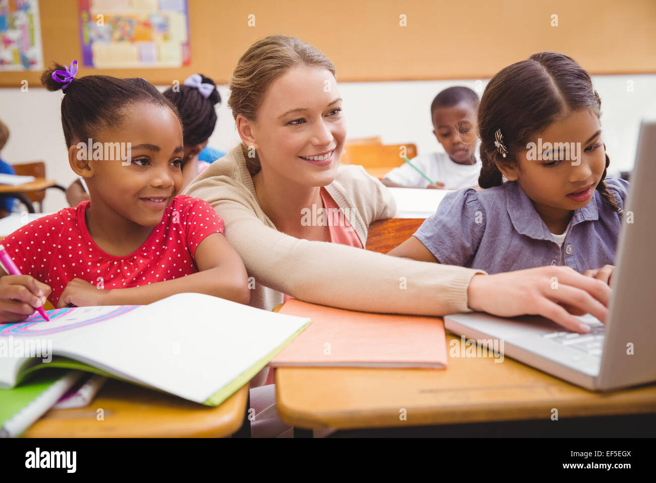 Cute pupil using computer with teacher Stock Photo - Alamy