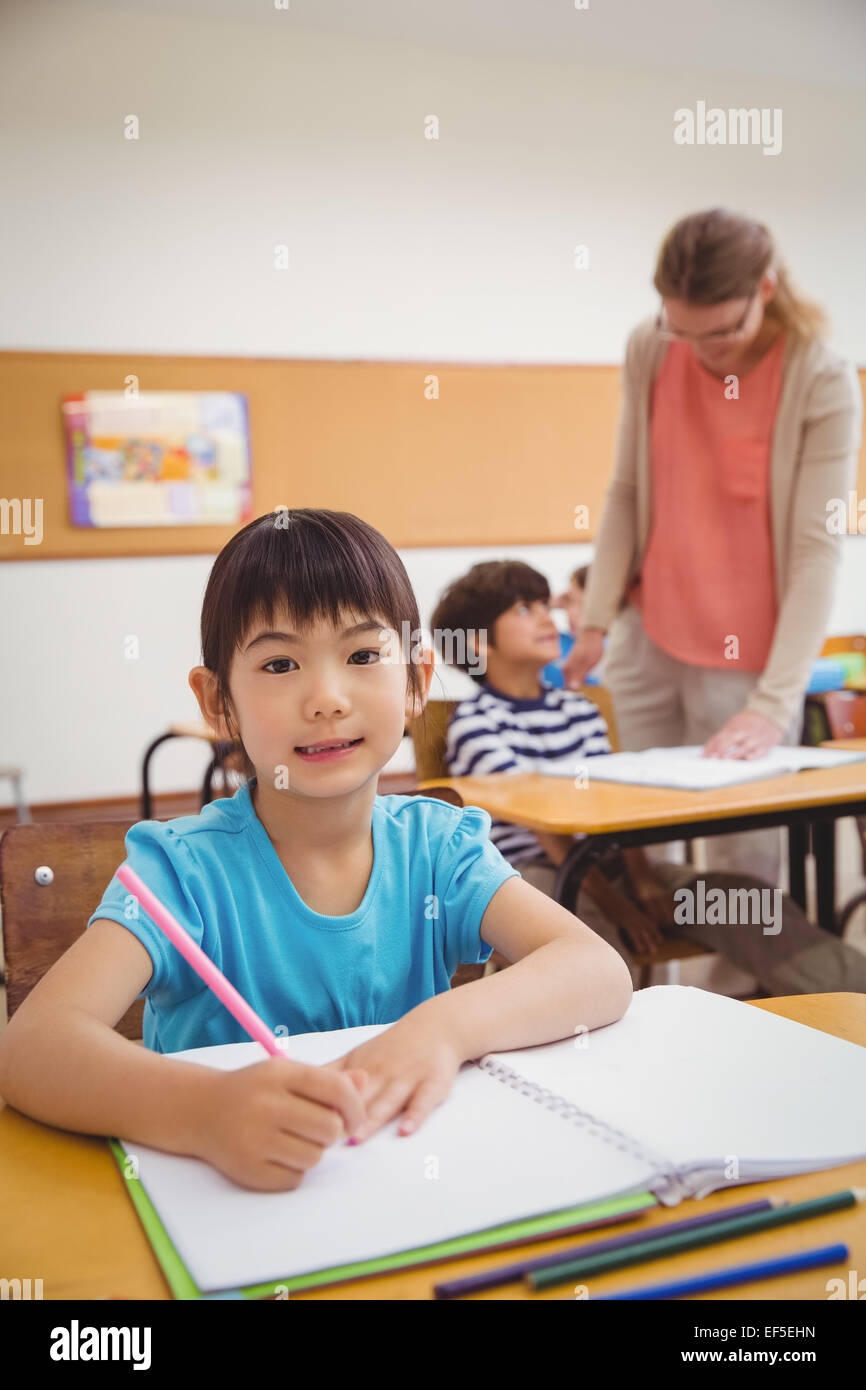 Cute pupils writing at desk in classroom Stock Photo - Alamy